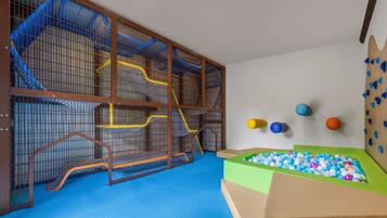 Uma área de recreação com estrutura de escalada, piscina de bolinhas e parede de escalada.