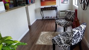 Um saguão com balcão de recepção, refrigerador de Pepsi, um quadro, tapete estampado e uma cadeira com revestimento floral.