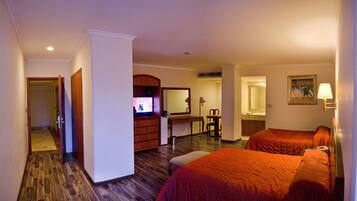 Quarto de hotel com duas camas, uma mesa de trabalho com cadeira, televisão e banheiro.