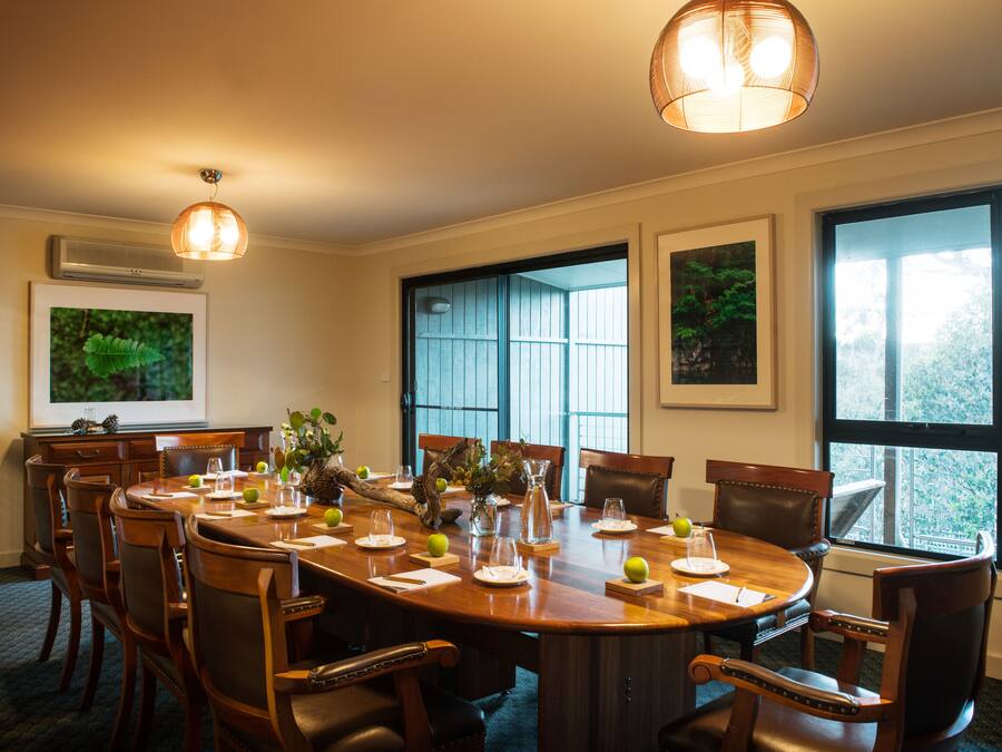 Uma sala de conferências com uma grande mesa oval, várias cadeiras e quadros nas paredes.