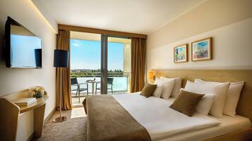 Quarto de hotel com uma cama grande, uma escrivaninha, uma televisão e vista para o exterior.