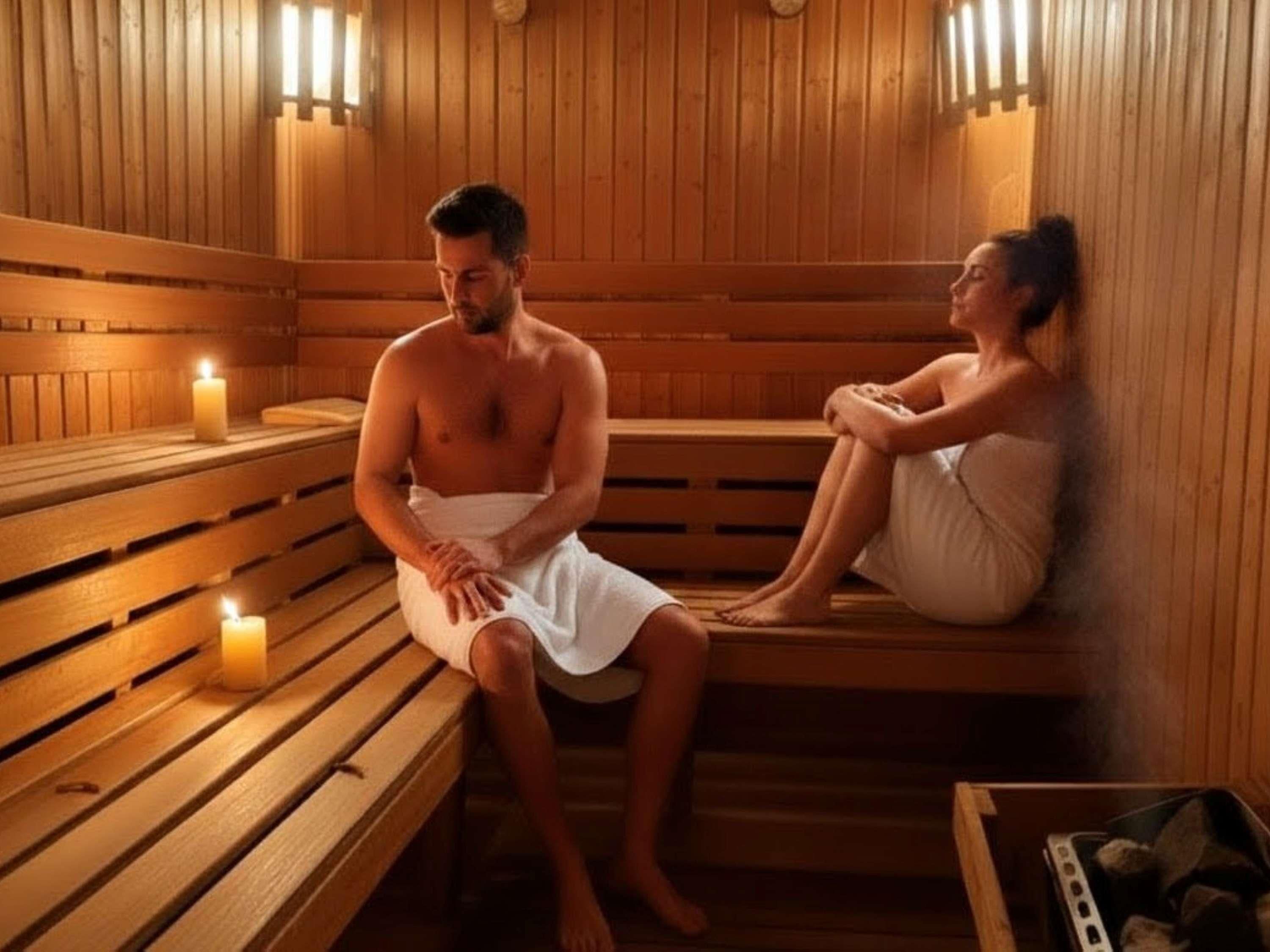 Uma sauna com bancos de madeira, velas e aquecedor visível.