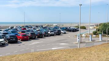 Um estacionamento com vários carros e vista para a praia ao fundo.