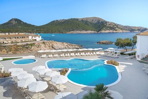 Área de piscina do resort com várias piscinas, espreguiçadeiras e guarda-sóis.