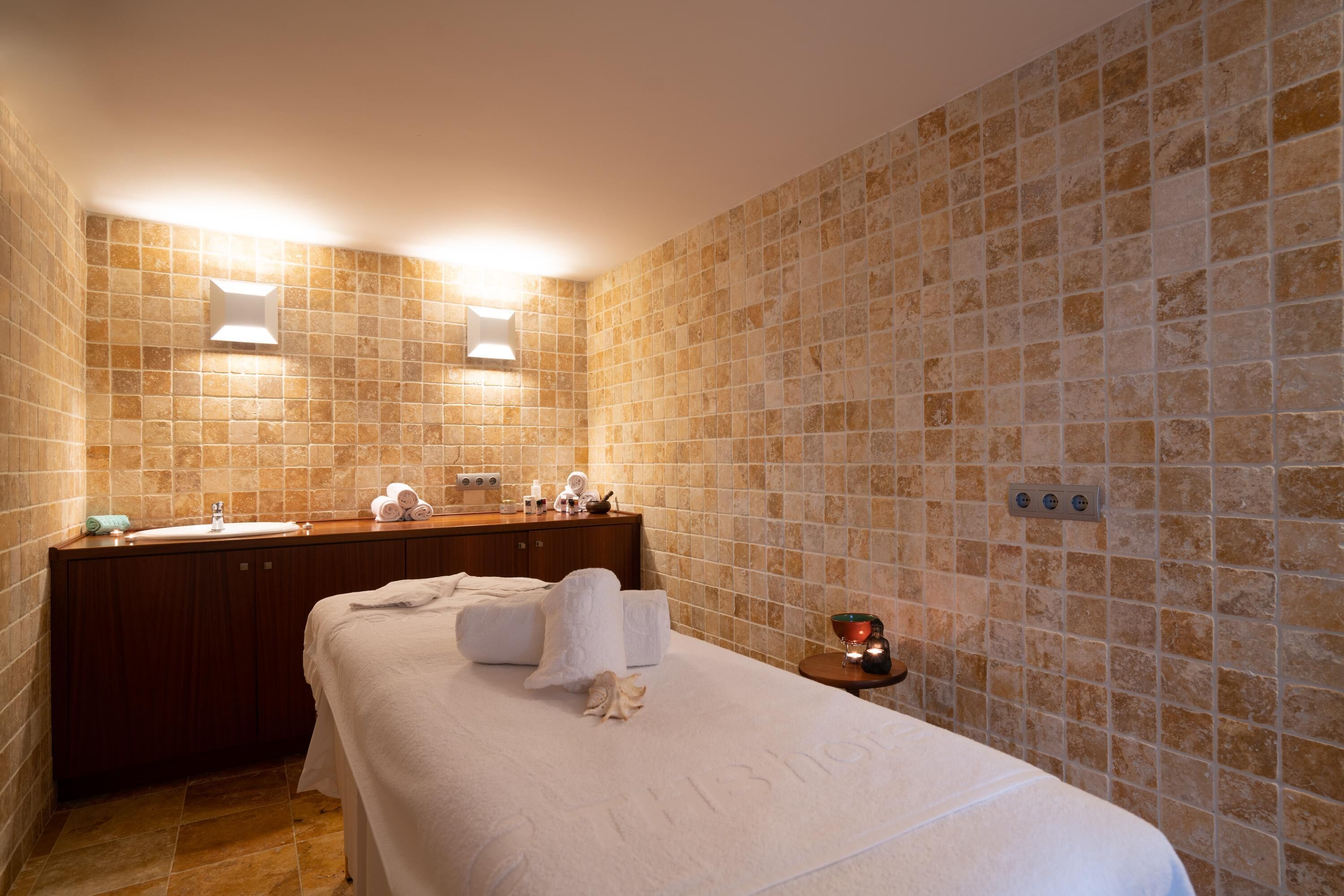 Quarto de hotel com uma cama, uma penteadeira de madeira com espelho e uma pia.