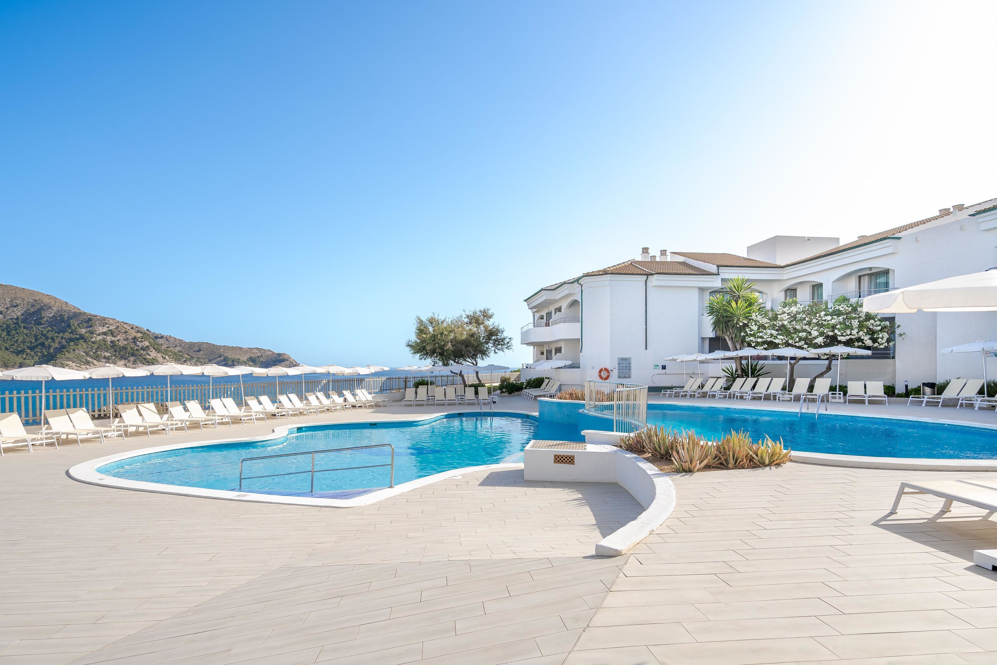 Área de piscina com espreguiçadeiras e vista para o mar.