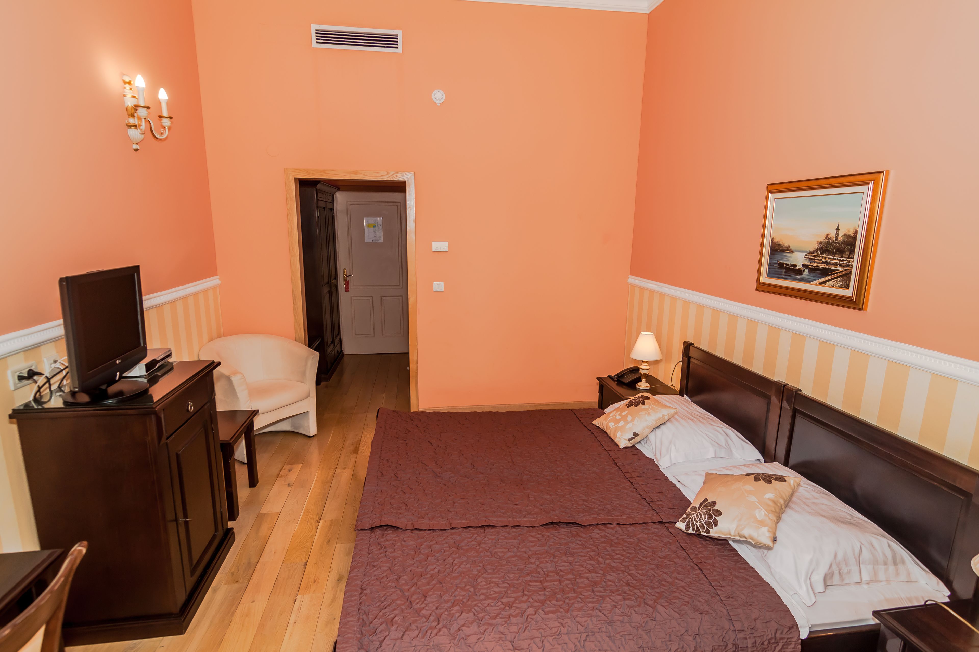 Um quarto com uma cama, televisão, escrivaninha e uma cadeira.
