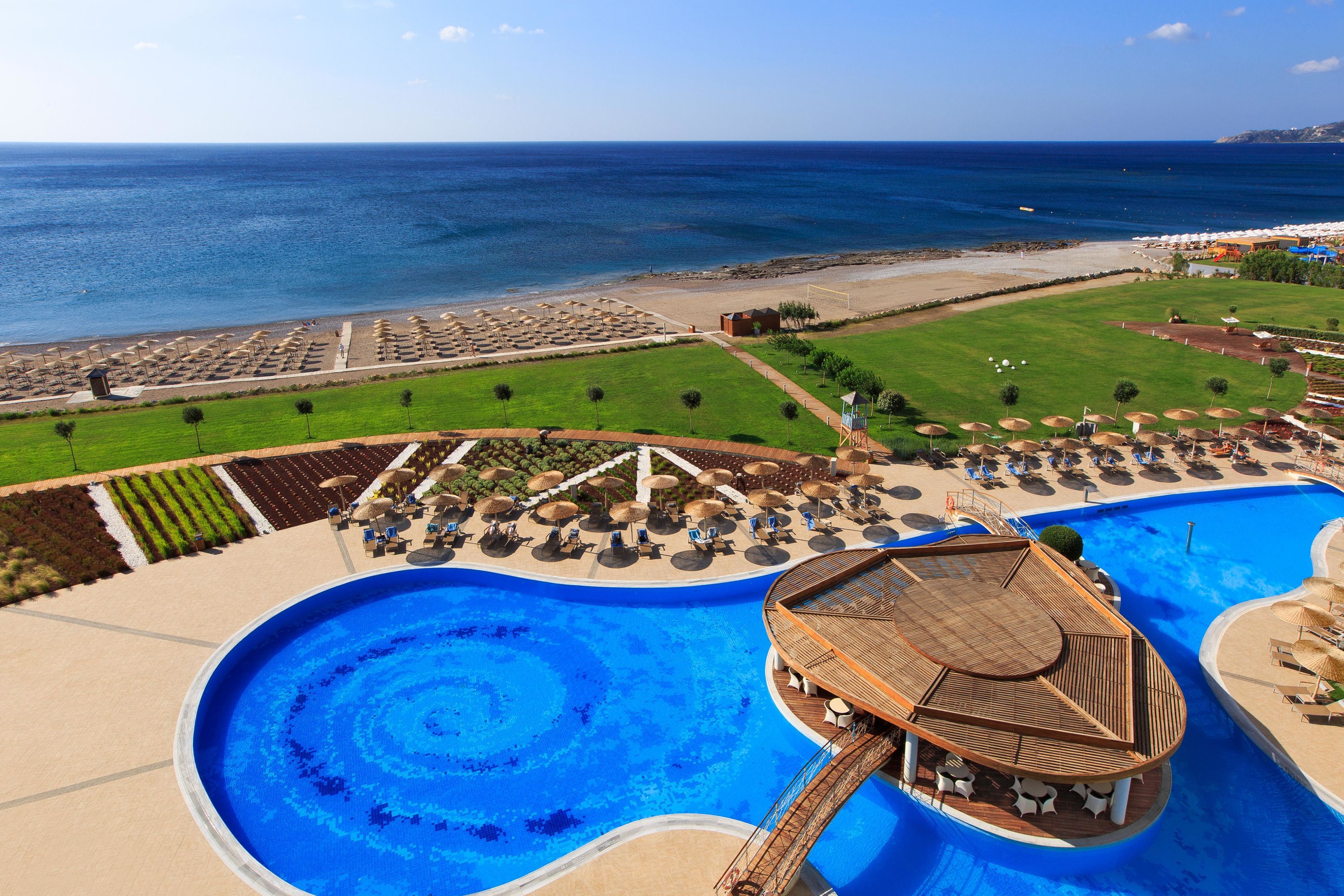 Um resort com uma piscina grande, área de praia e vista para o oceano.