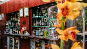 Uma área de bar com prateleiras de garrafas de bebidas, um refrigerador e um balde.