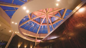 Um interior moderno com estrutura de teto de vidro central e painéis de madeira.