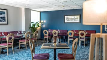 Um restaurante com cabines e mesas, algumas com copos de vinho.