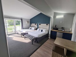 Quarto moderno com duas camas, uma kitchenette e uma varanda.