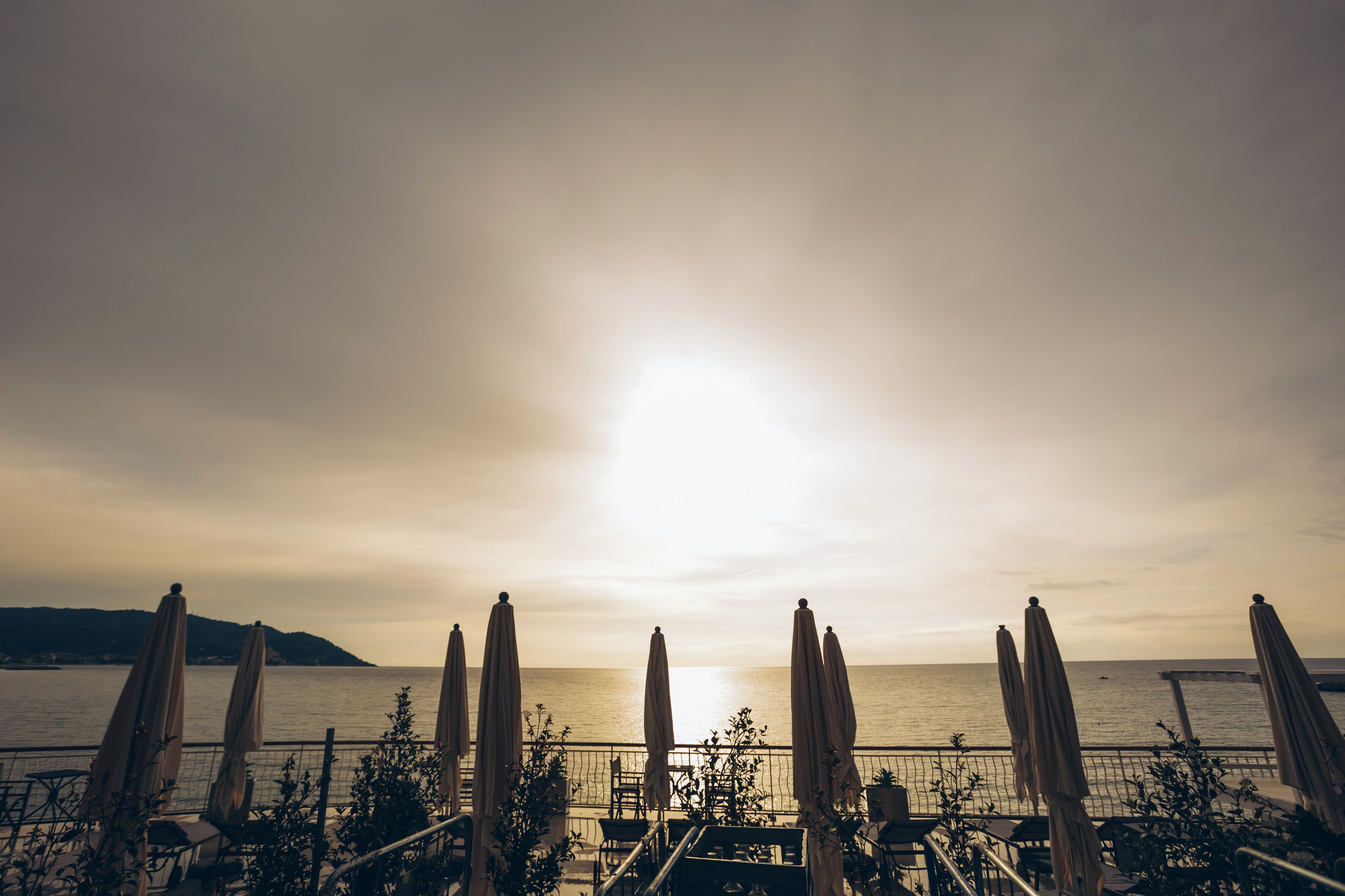 Terraço à beira-mar com guarda-sóis e cadeiras, com vista para o oceano.