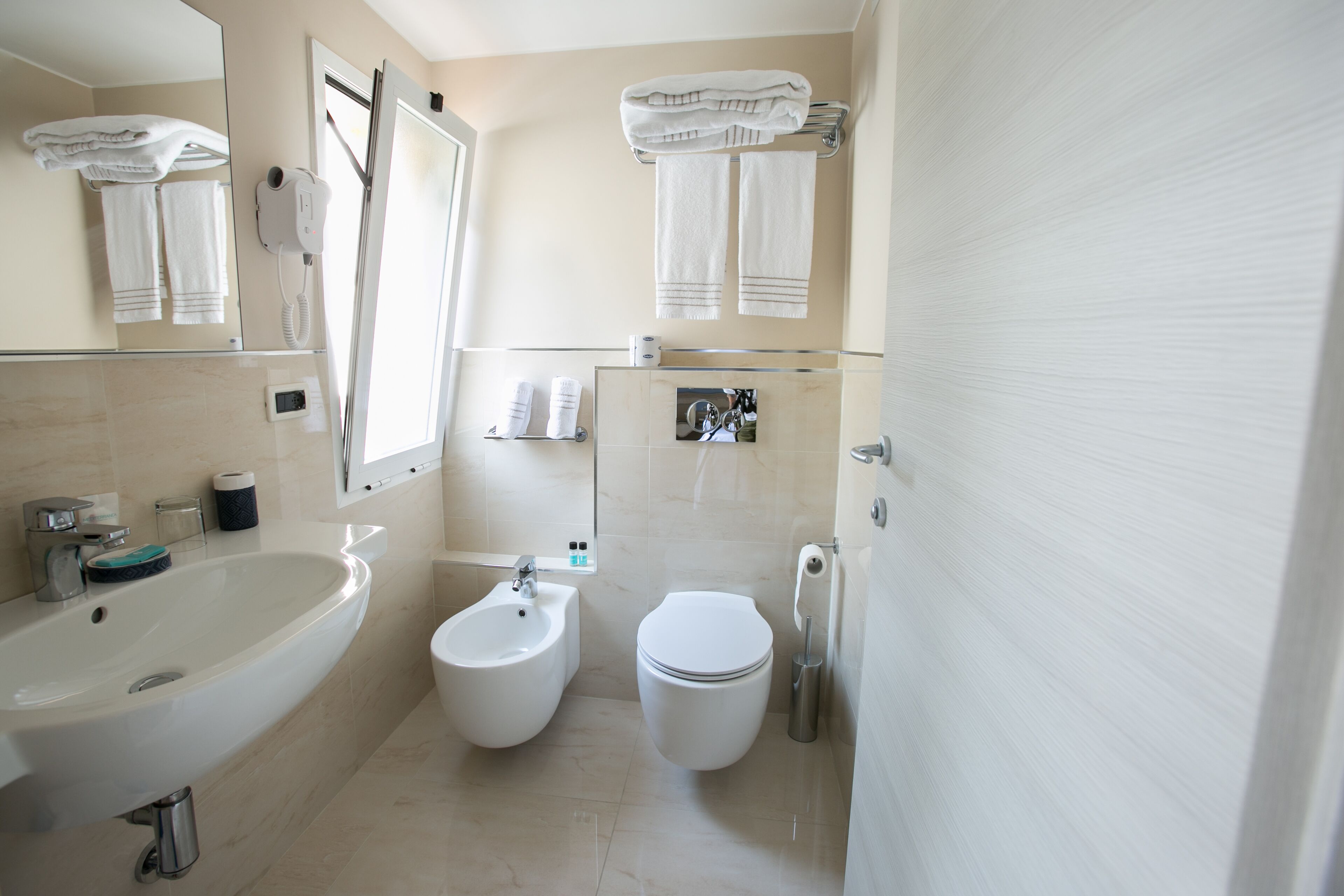 Casa de banho moderna com lavatório, bidé, sanita e porta-toalhas.