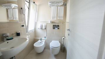 Casa de banho moderna com lavatório, bidé, sanita e porta-toalhas.