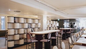 Um restaurante moderno com mesas redondas, cadeiras acolchoadas e um balcão central.