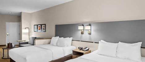 Quarto de hotel com duas camas, uma mesinha de cabeceira com telefone, abajur e uma pequena mesa com cafeteira.