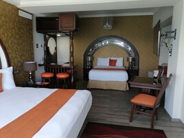 Quarto de hotel com duas camas, uma escrivaninha, uma cadeira e um espelho.