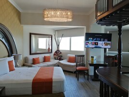 Quarto de hotel com cama, sofá, televisão e mesa de jantar.