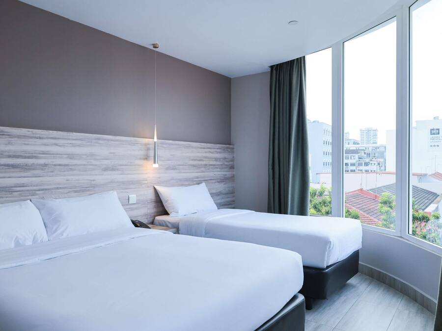 Quarto de hotel com duas camas, uma janela grande e vista para a cidade.