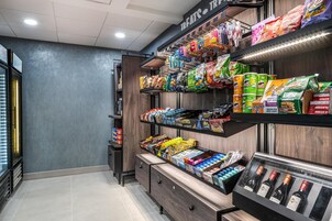 Passadeira com diversos lanches embalados e uma área refrigerada com garrafas de vinho.