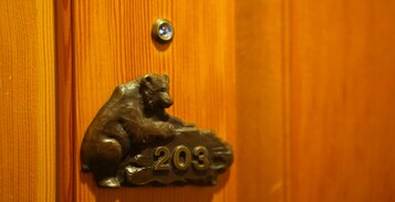 Campainha de latão com desenho de urso e o número 203.
