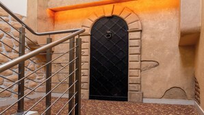 Uma escadaria com corrimão de metal, uma porta preta na base e uma parede decorativa com uma obra de arte emoldurada acima.