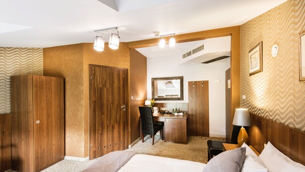 Quarto de hotel com uma cama grande, uma escrivaninha com cadeira, um guarda-roupa e um espelho.