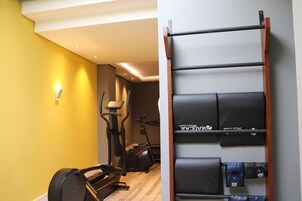 Ginásio doméstico com equipamentos de exercício, incluindo esteira, elíptica e bicicleta ergométrica.