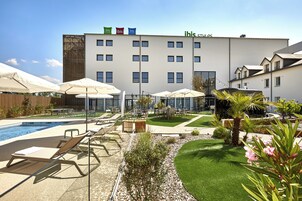 Um hotel com piscina, área de estar ao ar livre e um jardim bem cuidado.