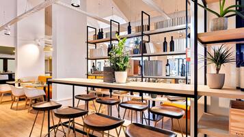 Uma área de bar moderna com banquetas, prateleiras com garrafas e plantas em vasos.