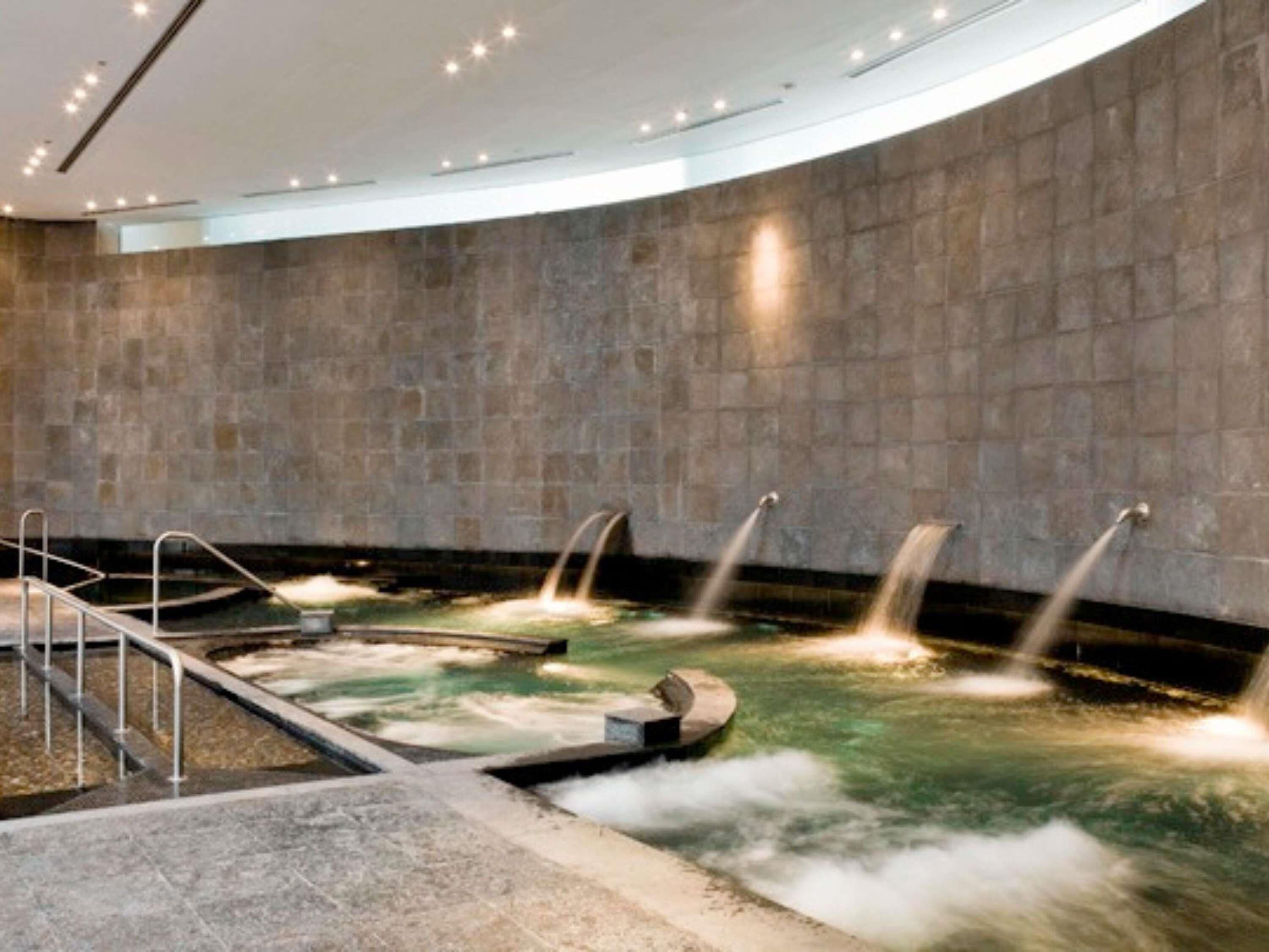 Uma área de spa com várias banheiras de hidromassagem e uma parede de pedra.