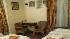 Quarto de hotel com duas camas de solteiro, uma escrivaninha e uma cadeira.