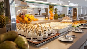 Buffet com diversos alimentos, incluindo frutas, sobremesas e petiscos.
