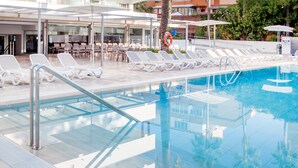Área de piscina com espreguiçadeiras, um flutuador de salva-vidas e piscina transparente.