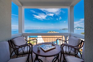 Varanda com vista para o mar, duas cadeiras, uma mesa com um tabuleiro de xadrez e uma chávena.