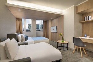 Quarto de hotel moderno com uma cama, uma escrivaninha e vista para a cidade.