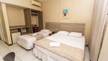 Quarto de hotel com duas camas, um guarda-roupa, uma escrivaninha e um ar condicionado.