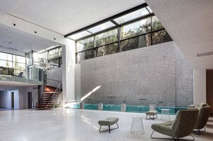 Um hall amplo com teto alto, escada e área de estar com cadeiras e pufes.