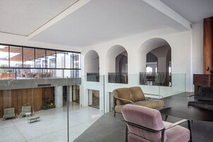 Um hall amplo com tetos altos, portas em arco e áreas de estar modernas.