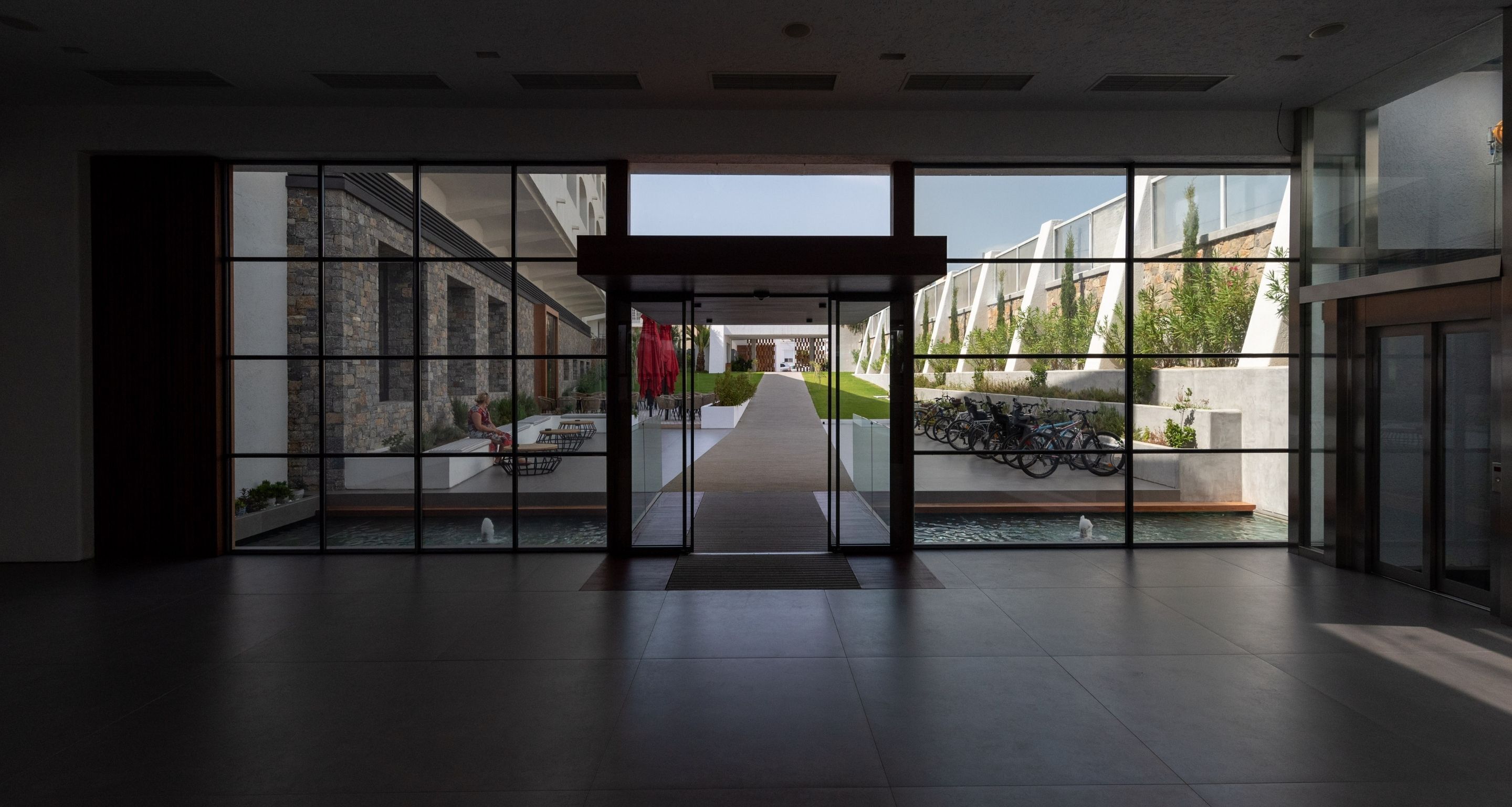 Entrada moderna de hotel com porta de vidro que dá para área externa coberta.