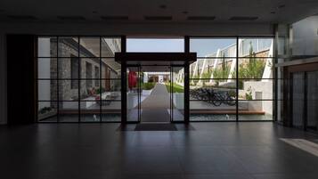 Entrada moderna de hotel com porta de vidro que dá para área externa coberta.