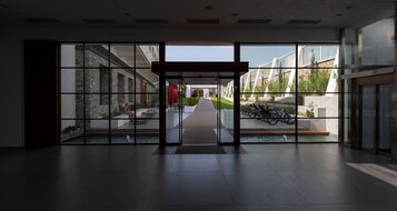 Entrada moderna de hotel com porta de vidro que dá para área externa coberta.