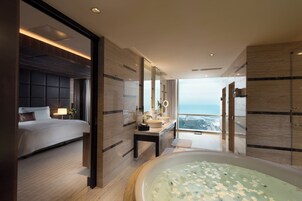 Quarto de hotel moderno com cama grande, banheiro com banheira e vista para a cidade.