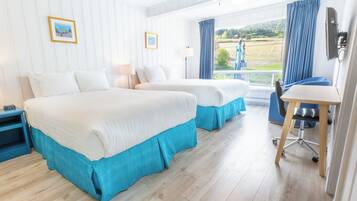 Quarto de hotel com duas camas, uma escrivaninha e uma janela com vista para o campo.