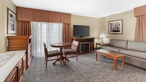 Quarto de hotel com televisão, sofá, mesa de jantar, cadeiras e lareira.