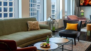 Uma sala moderna com um sofá verde, uma poltrona preta e uma mesa de centro com petiscos.