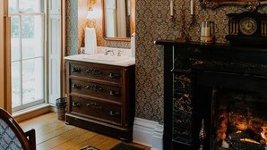Quarto com lareira, espelho, penteadeira e tapete estampado.