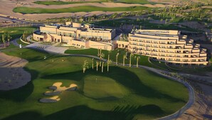Um grande resort com vários edifícios, um campo de golfe e palmeiras.
