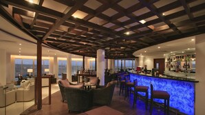 Uma área de bar moderna com balcão curvo, assentos e vista para a paisagem urbana.